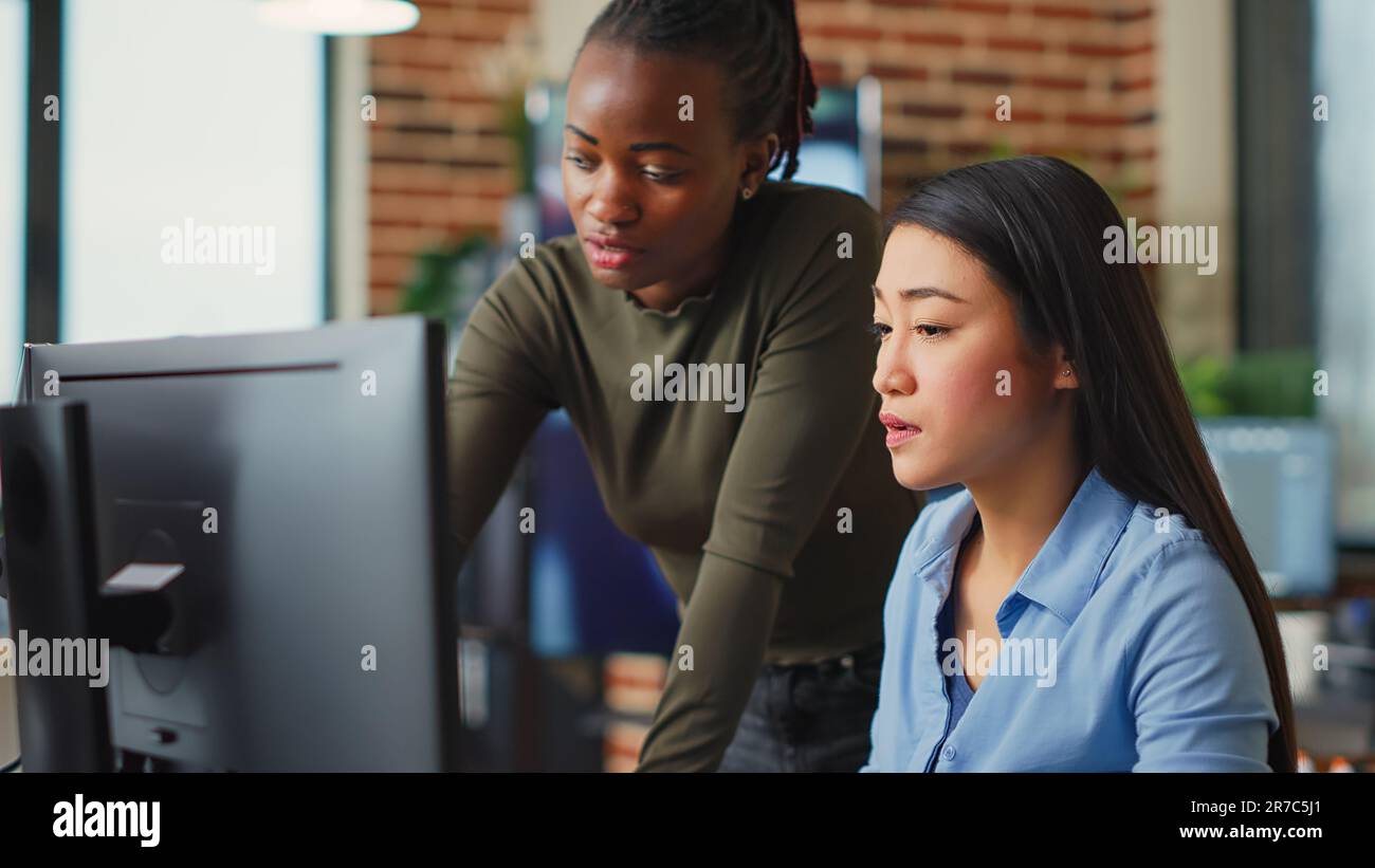 Multiethnic team of IT developers working on computers to create artistic machinery software ...