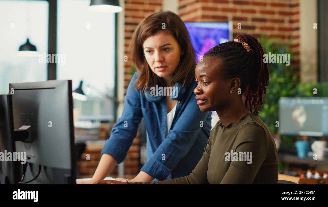 Team of diverse office employees working on multi monitors to create machinery software, using ...