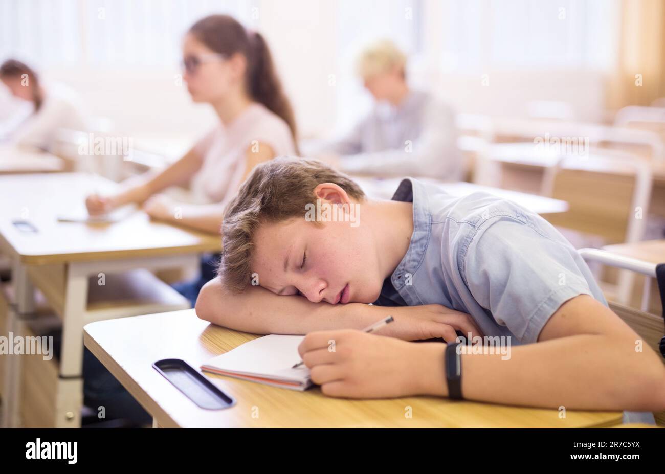 Teen student sleeping at desk in classroom during lesson Stock Photo ...