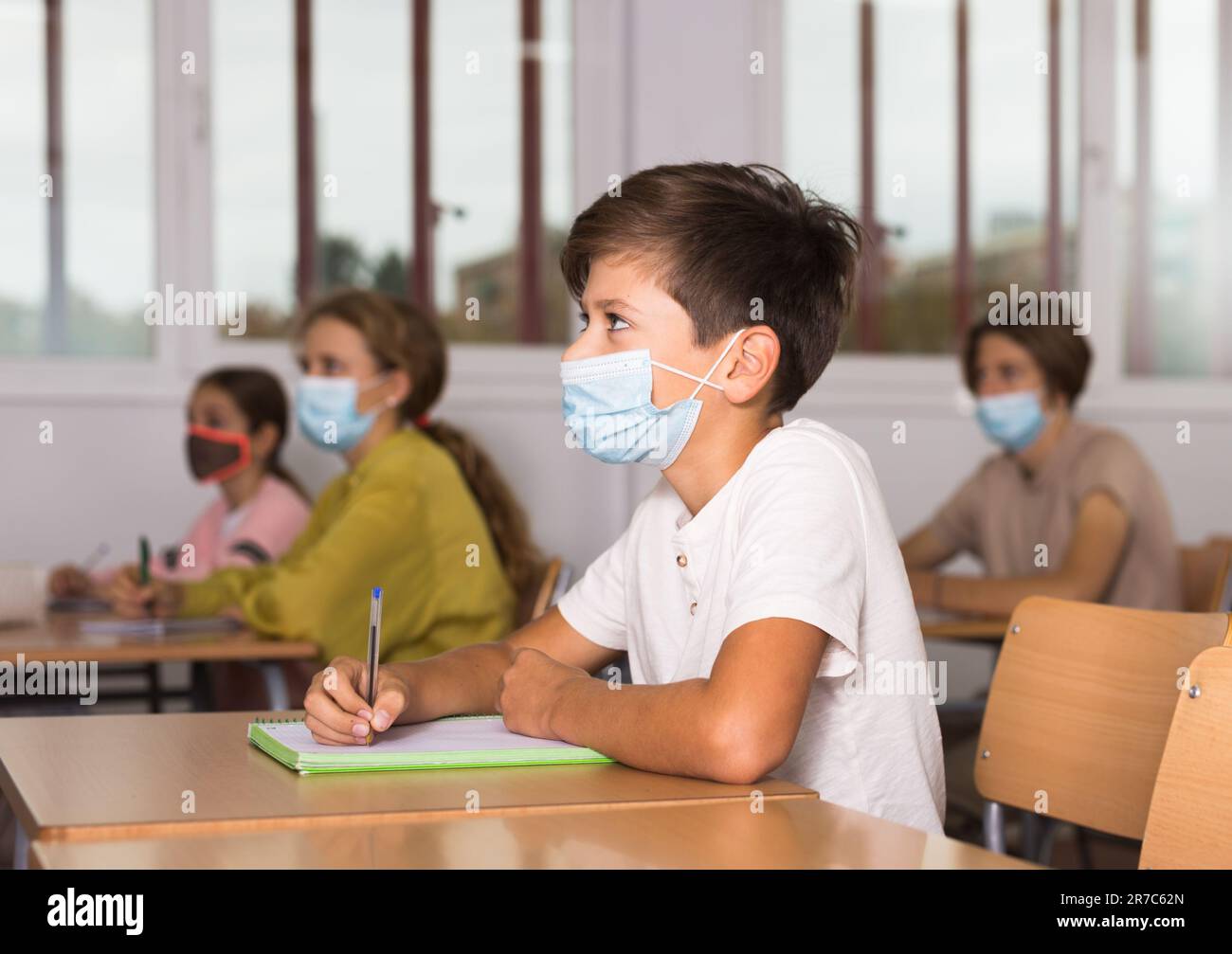 Schoolboy in mask sitting in classroom during lesson Stock Photo - Alamy