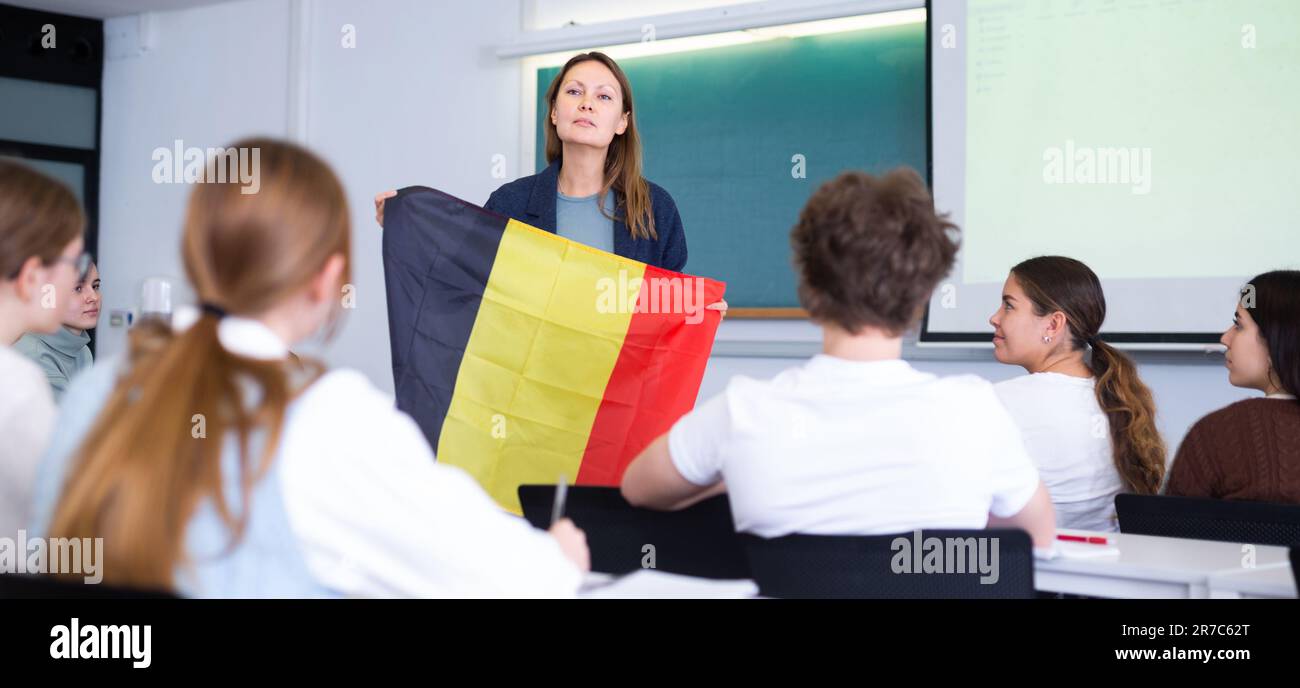 Female professor shows students flag of Belgium Stock Photo - Alamy