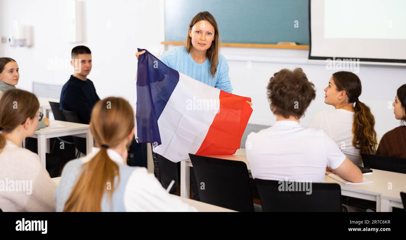 Adult female teacher showing French flag to students Stock Photo - Alamy