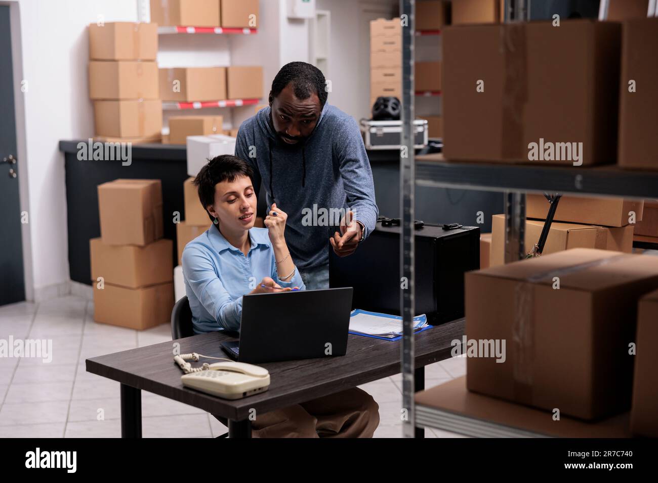 Warehouse employees analyzing transportation logistics on laptop ...