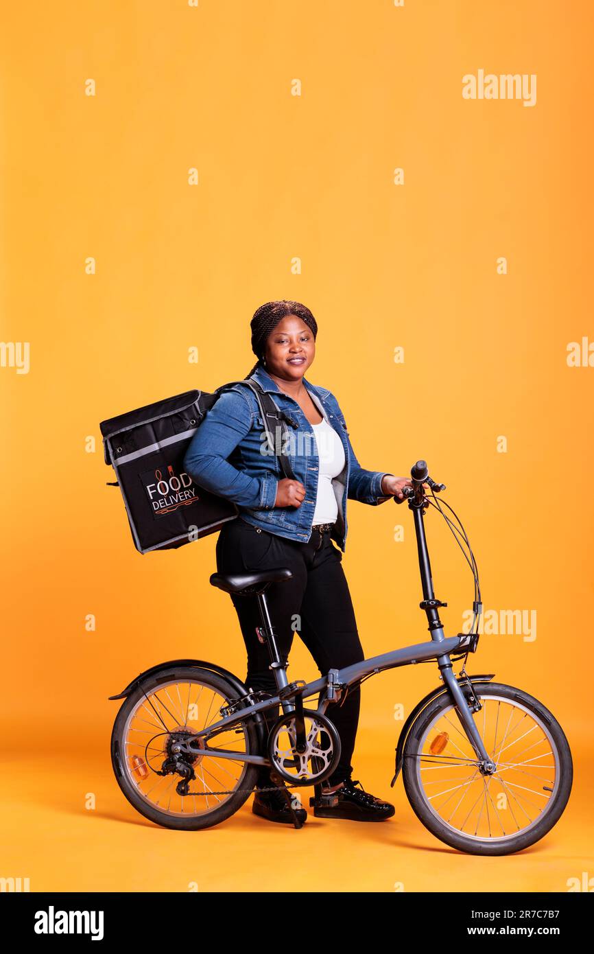 African american restaurant courier standing beside bike holding ...