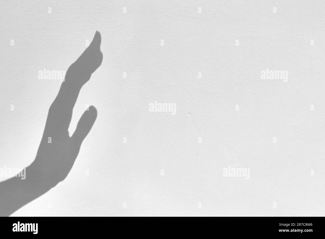 Shadow silhouette of hand raised in form of stop gesture, on gray ...