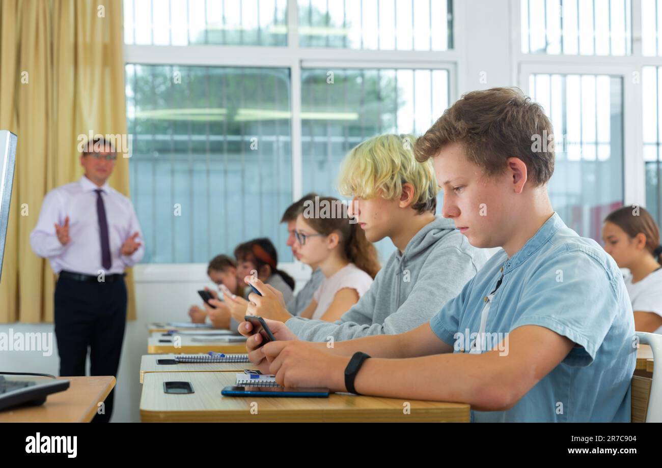 Modern teenagers sitting with mobile phones on lesson Stock Photo - Alamy