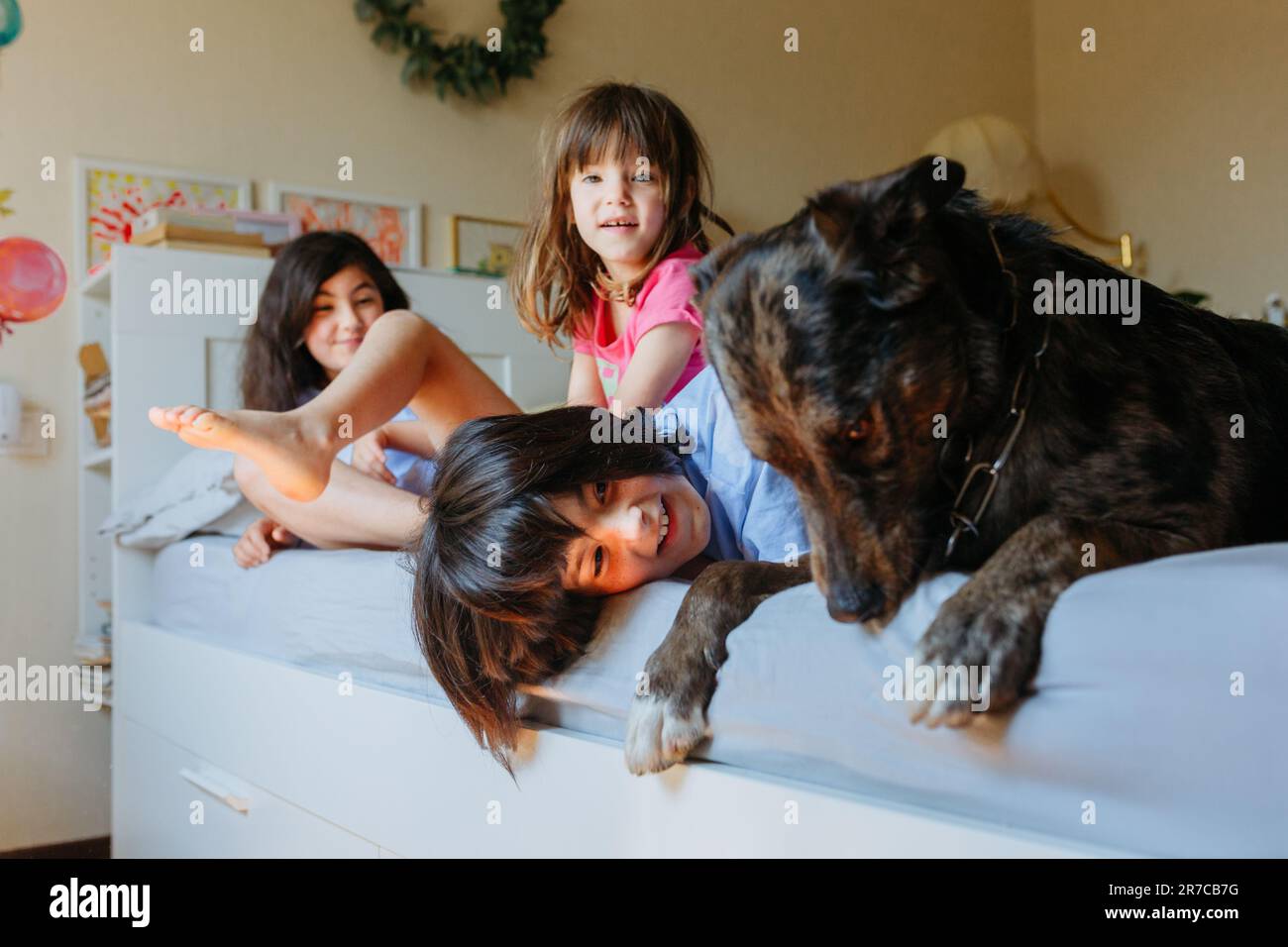 side view on three children sitting on the parents bed and playing with ...