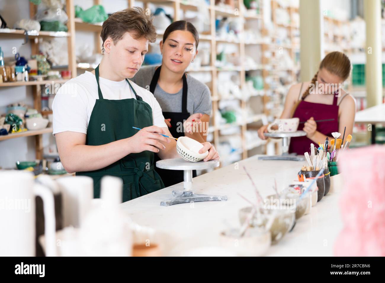 Female potter teaches guy how to apply design and glaze on pottery ...