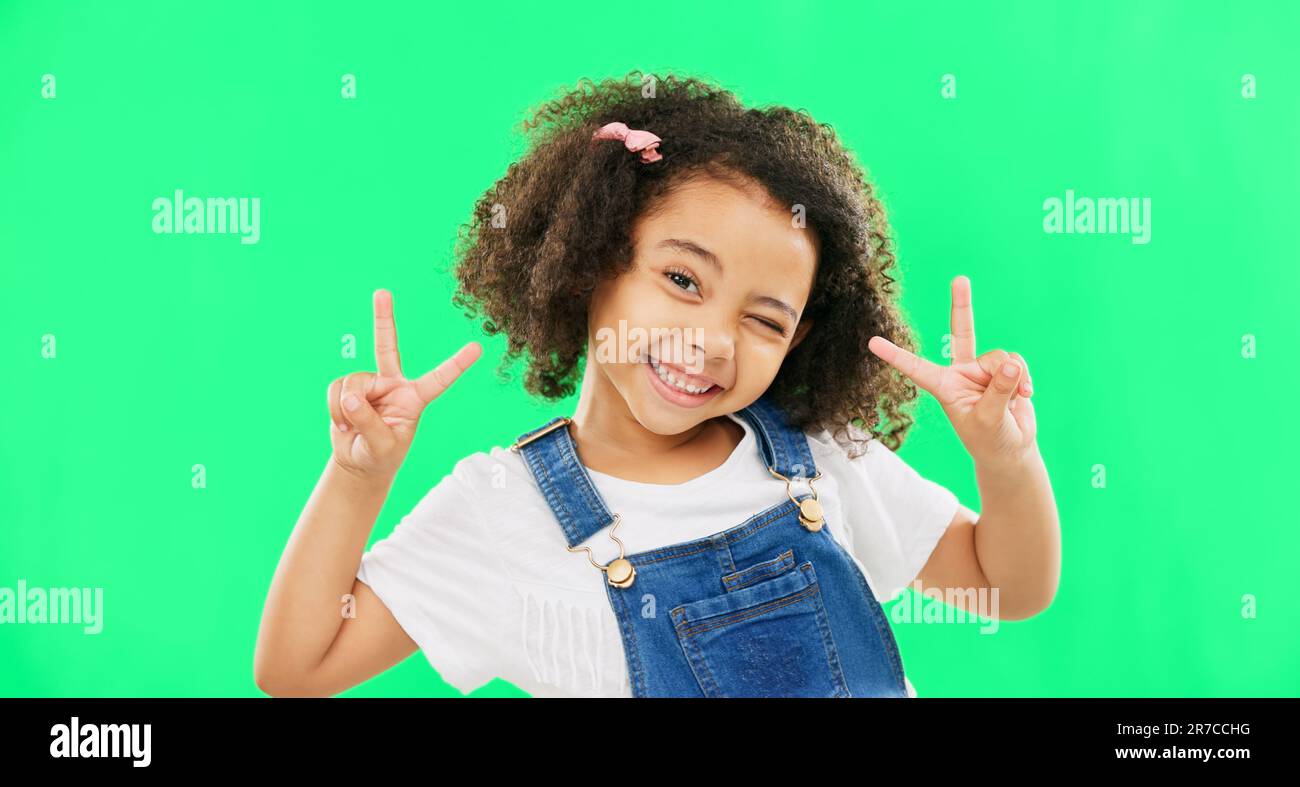 Face, smile and child with peace sign on green screen in studio ...