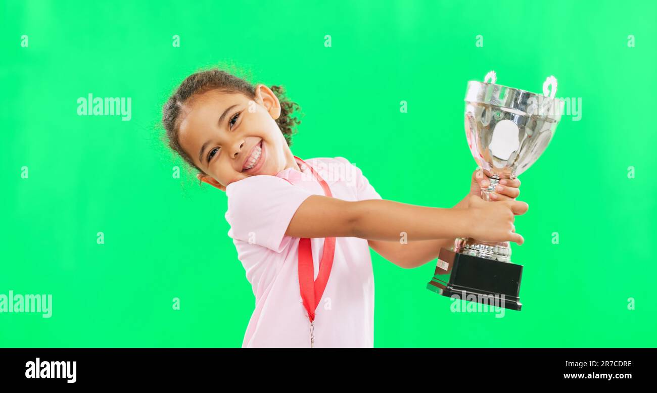 Happy, winning and face of child with a trophy isolated on a green ...