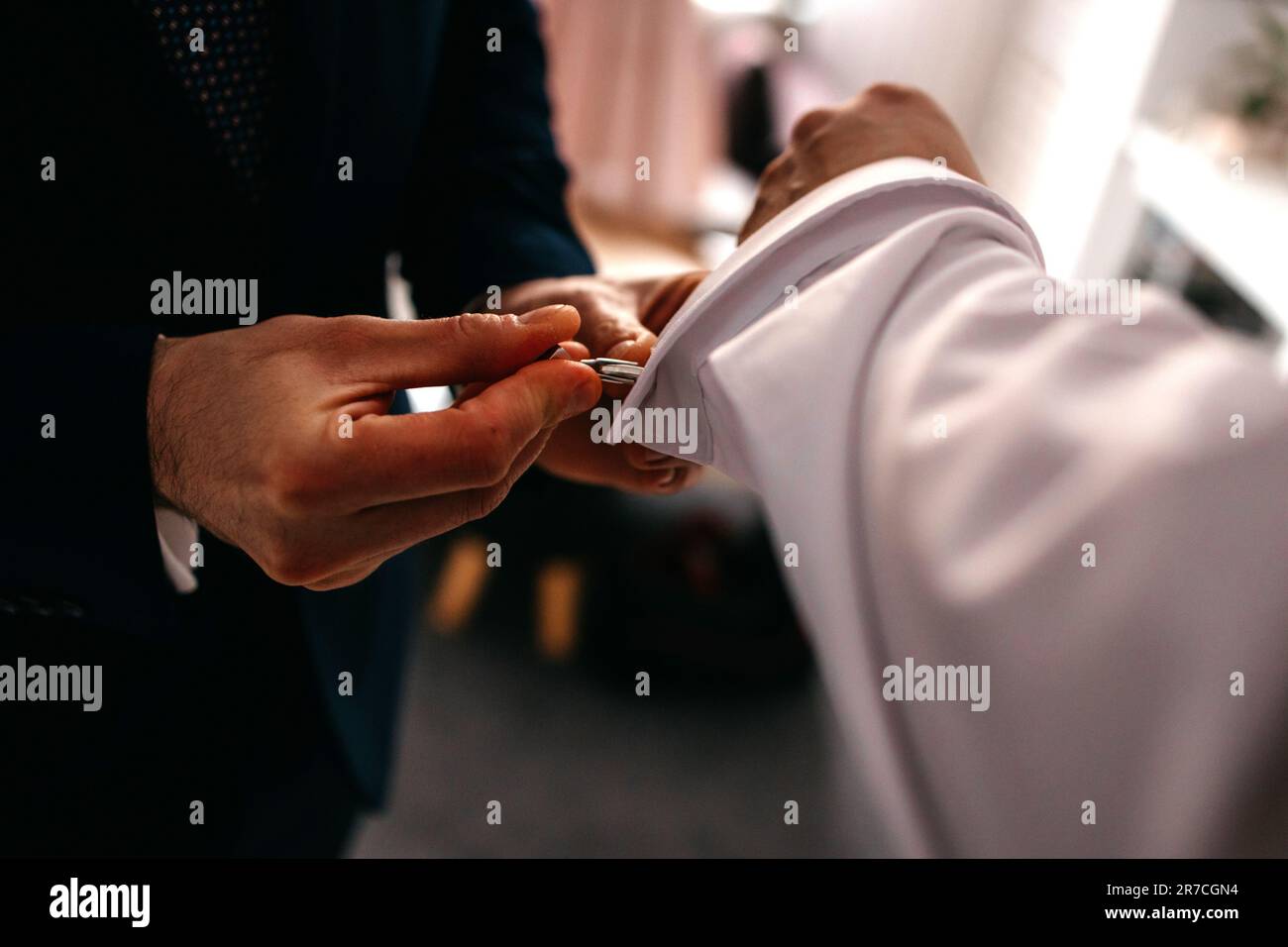 Man's style. dressing suit shirt and cuffs, closeup of hands helping to ...