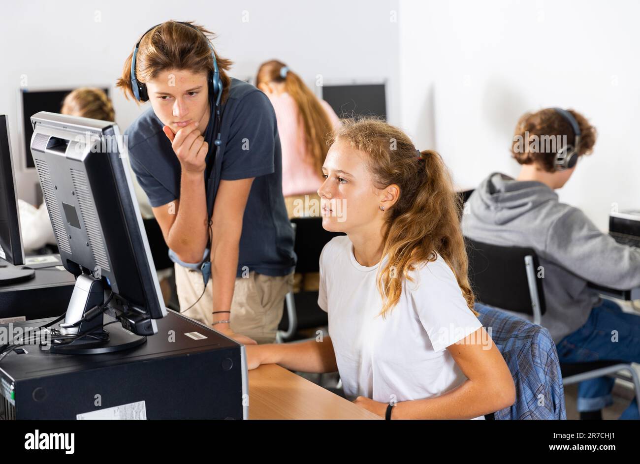 Group of teenage boys and girls learning to use computers in classroom ...