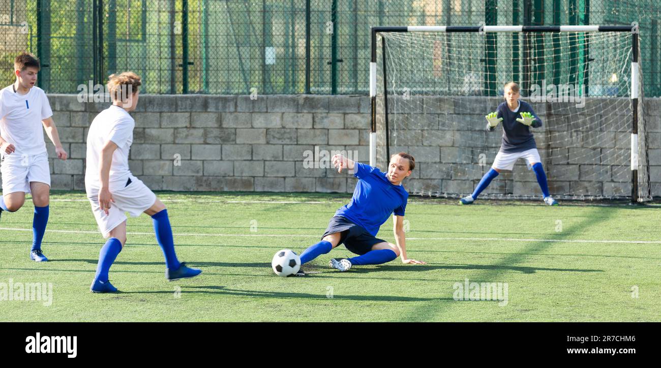 Game of football match between two teams of teenagers in white and blue ...