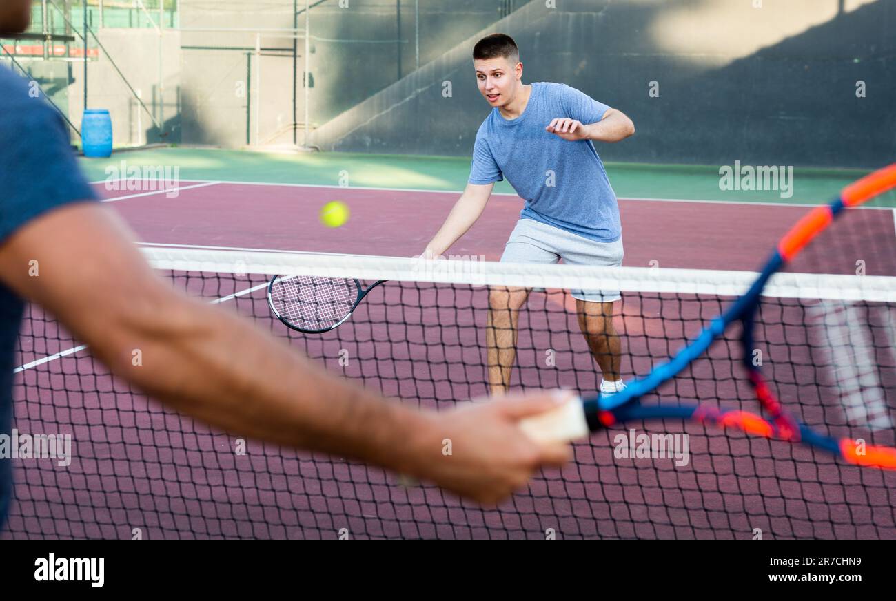 Concentrated young man tennis player hitting ball with racket Stock ...