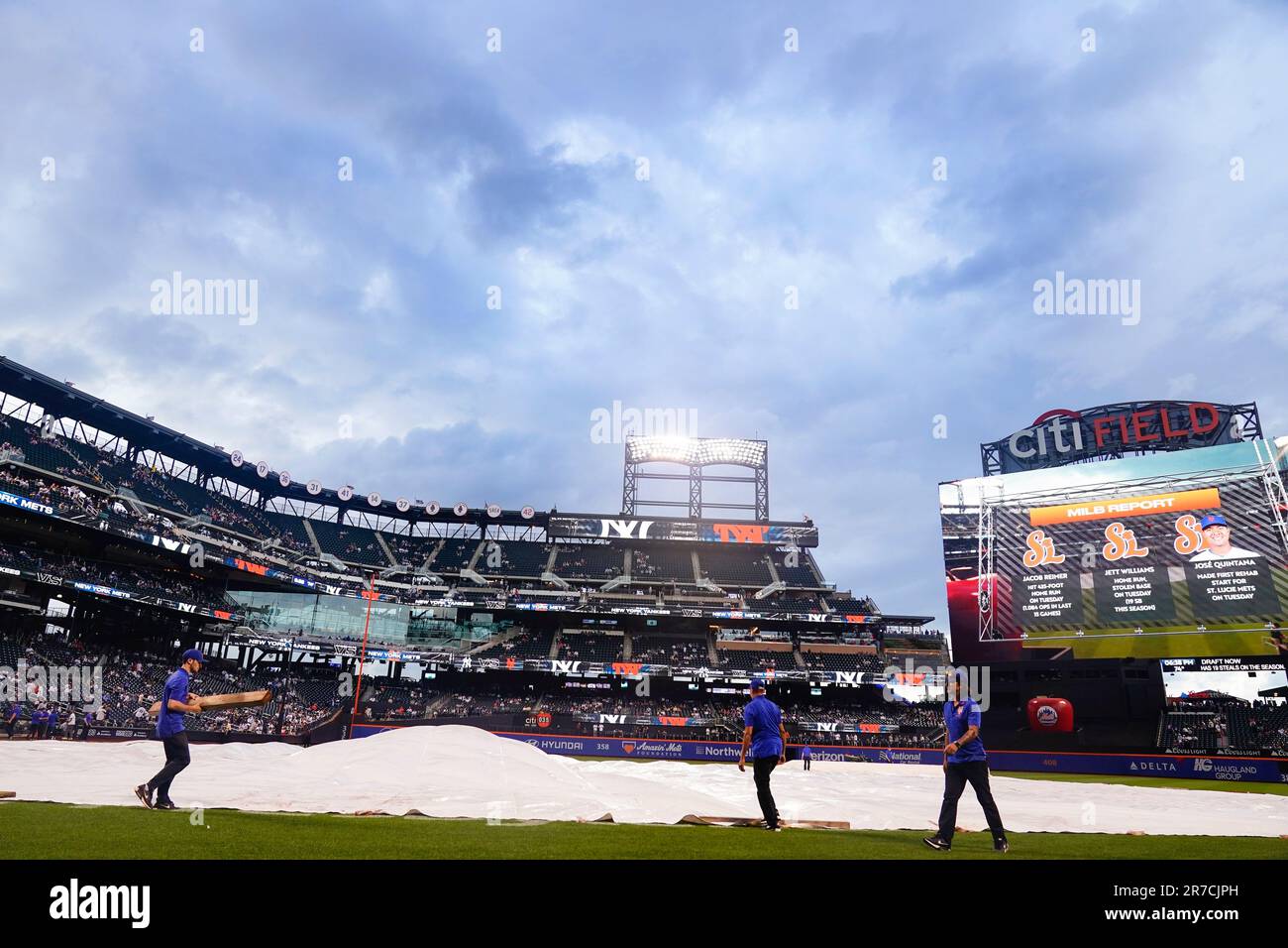 Grounds crew members cover the field before a baseball game between the ...
