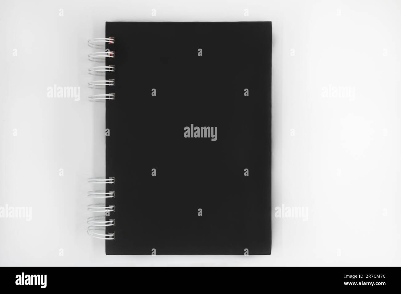 A closed black spiral-bound notebook on a white background, with copy ...