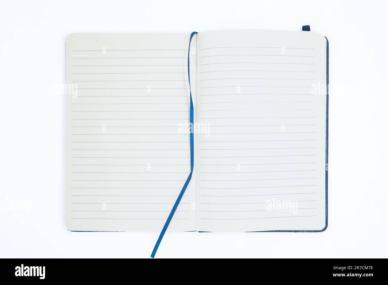 A blue hardcover notebook with white lined paper placed against a white ...