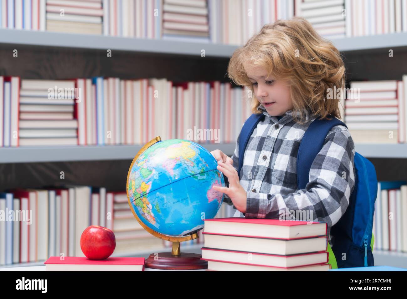 School pupil looking at globe in library, geography lesson. School ...