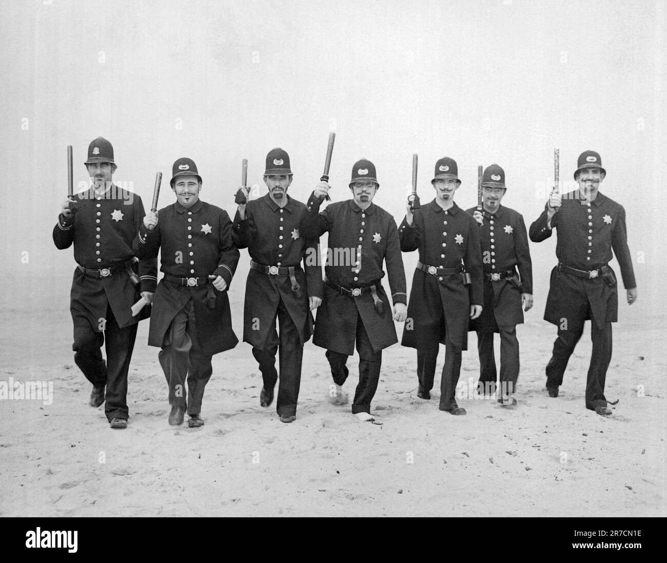 Hollywood, California, c 1940 A line of comedy cops on the beach with ...