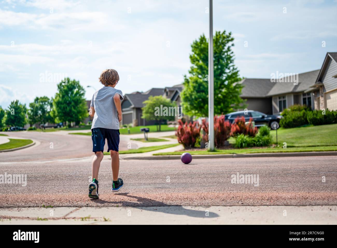Chasing a ball that has crossed the street by rolling into a road Stock ...