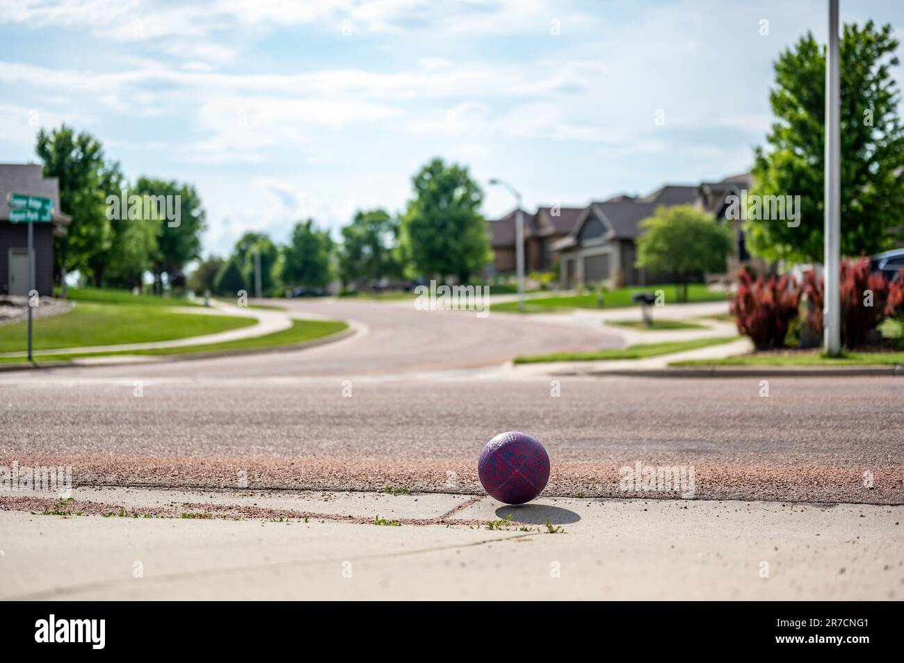 Chasing a ball that has crossed the street by rolling into a road Stock ...