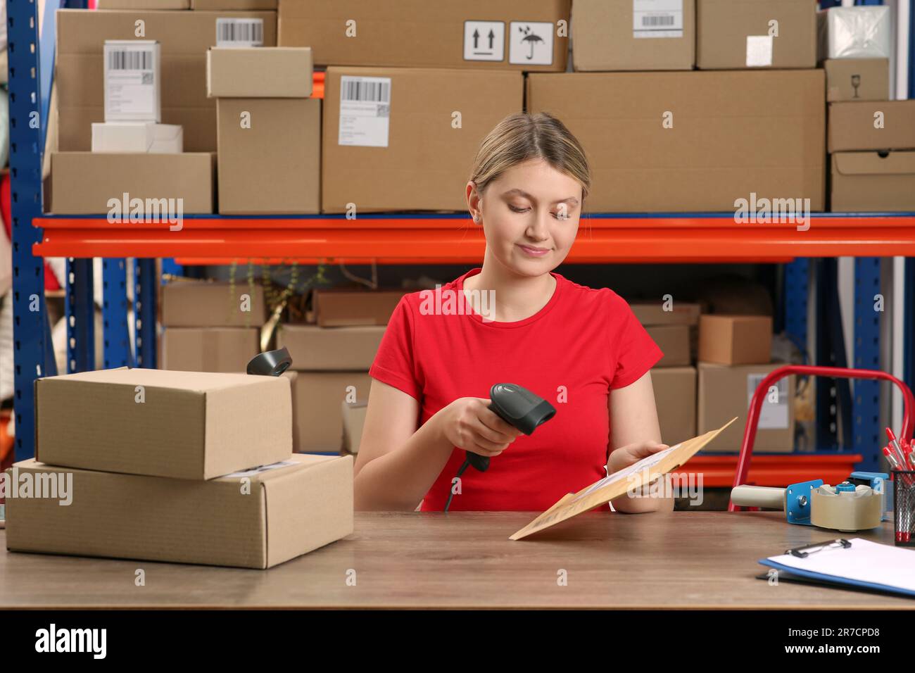 Post office worker with scanner reading parcel barcode at counter ...