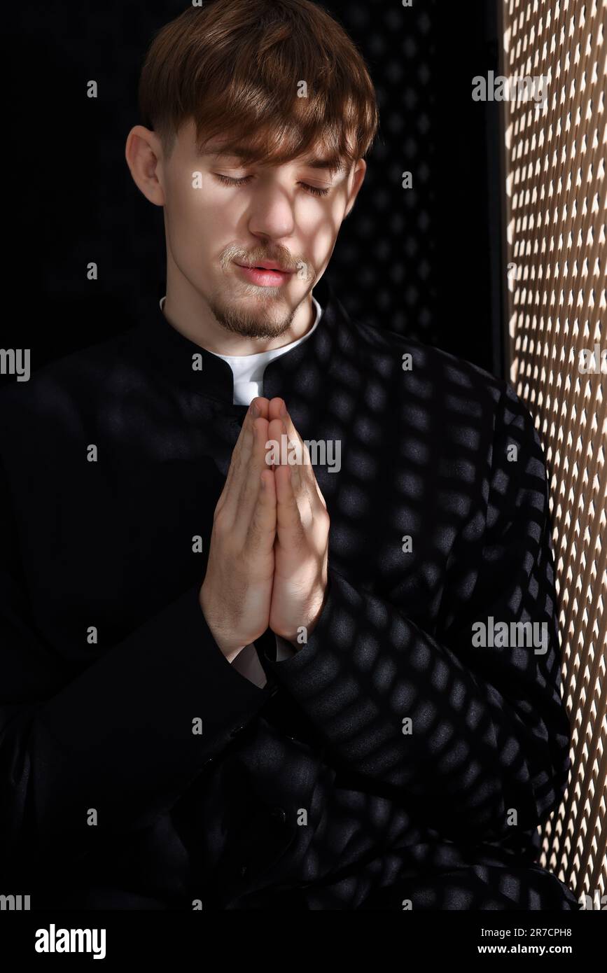 Catholic priest praying near wooden window in confessional booth Stock ...