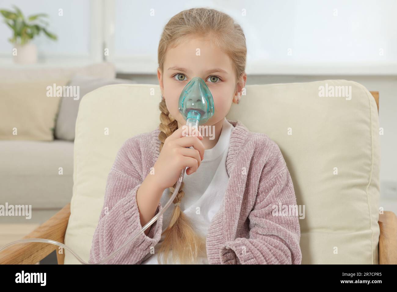Little girl using nebulizer for inhalation in armchair at home Stock ...