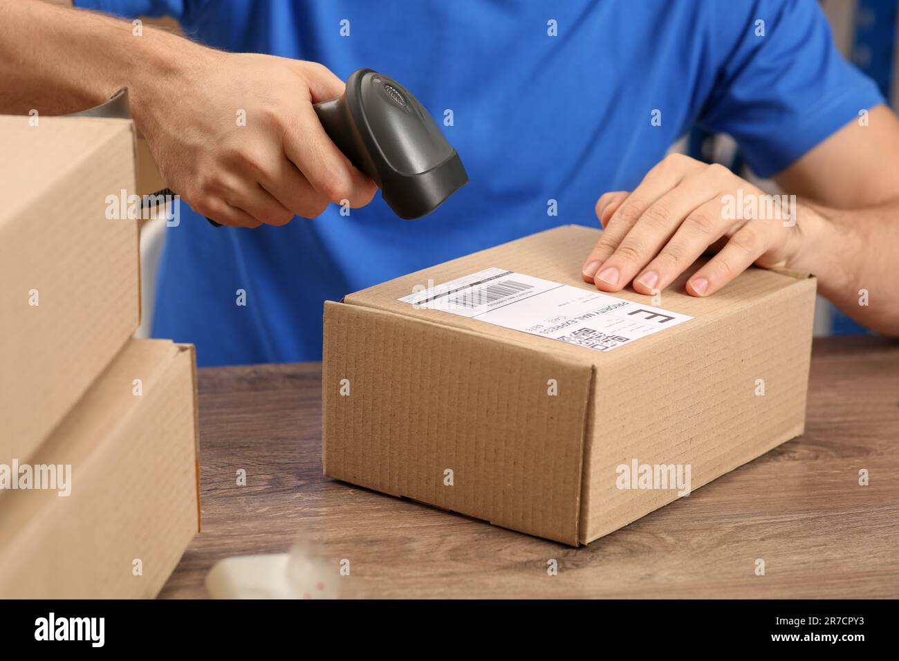 Post office worker with scanner reading parcel barcode at counter ...