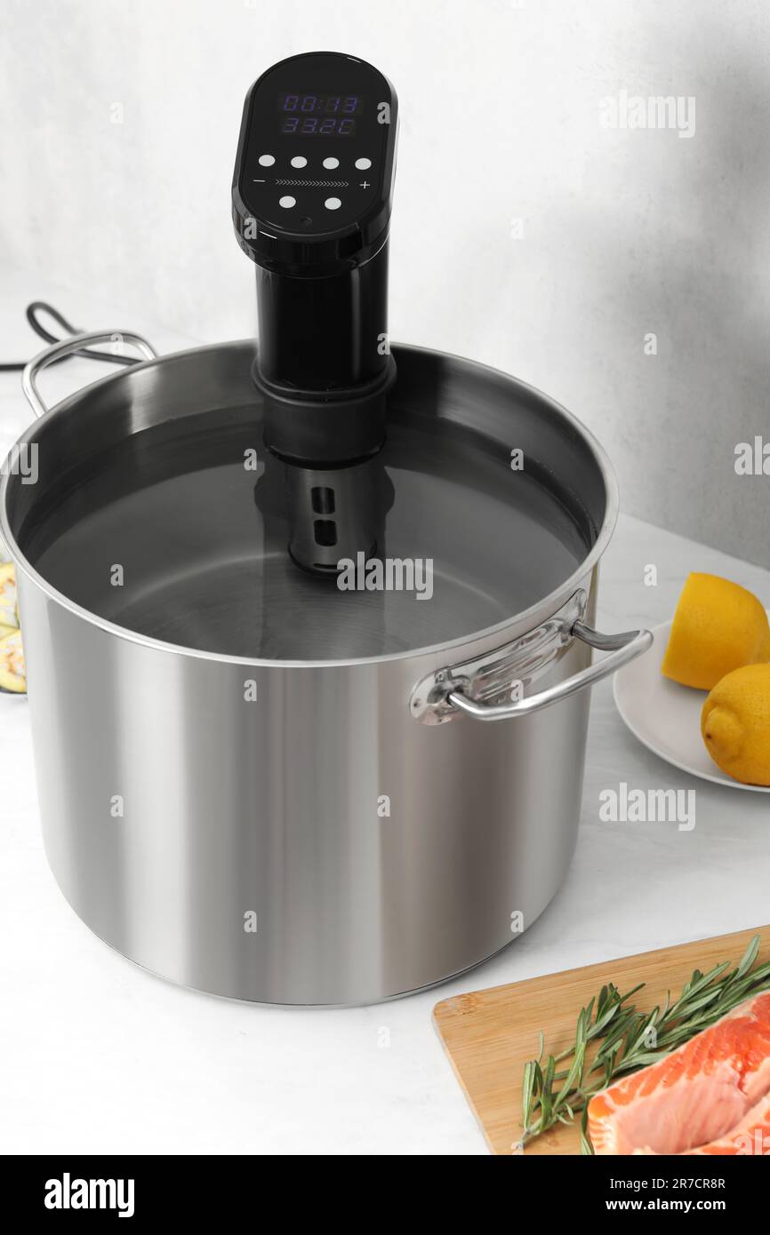 Sous vide cooker in pot on white table. Thermal immersion circulator ...