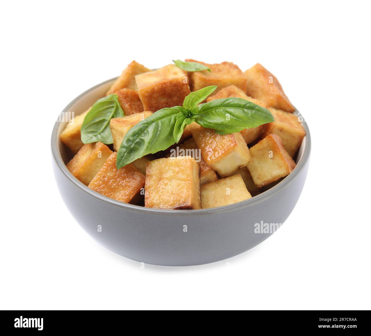 Bowl with delicious fried tofu and basil leaves on white background ...
