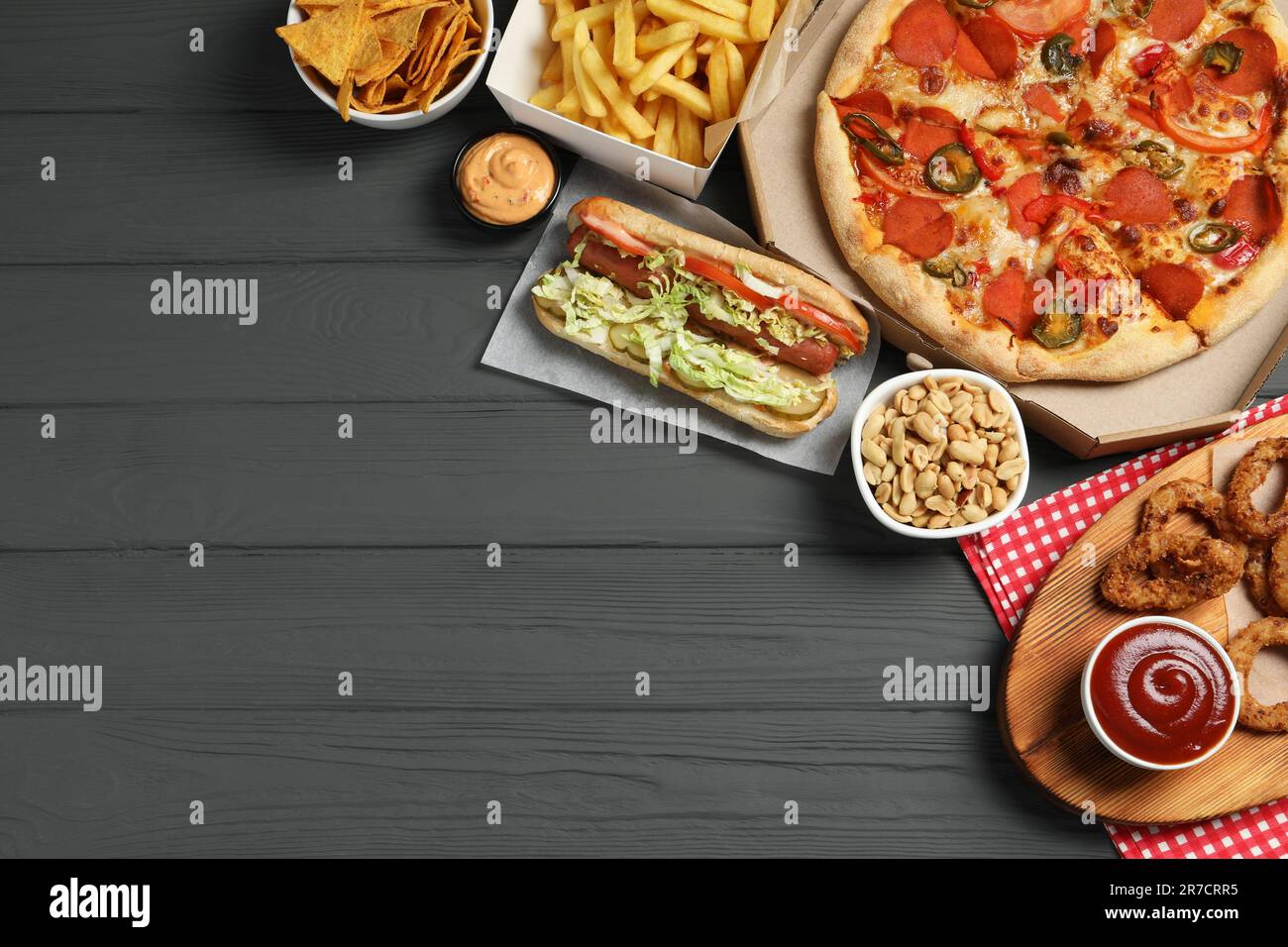 French fries, onion rings and other fast food on gray wooden table ...