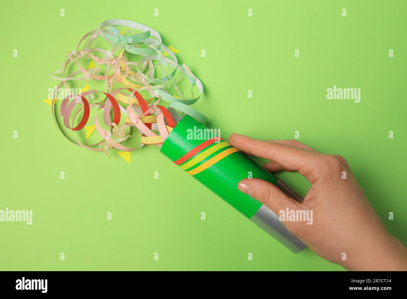 Woman holding party popper with serpentine and confetti on green ...