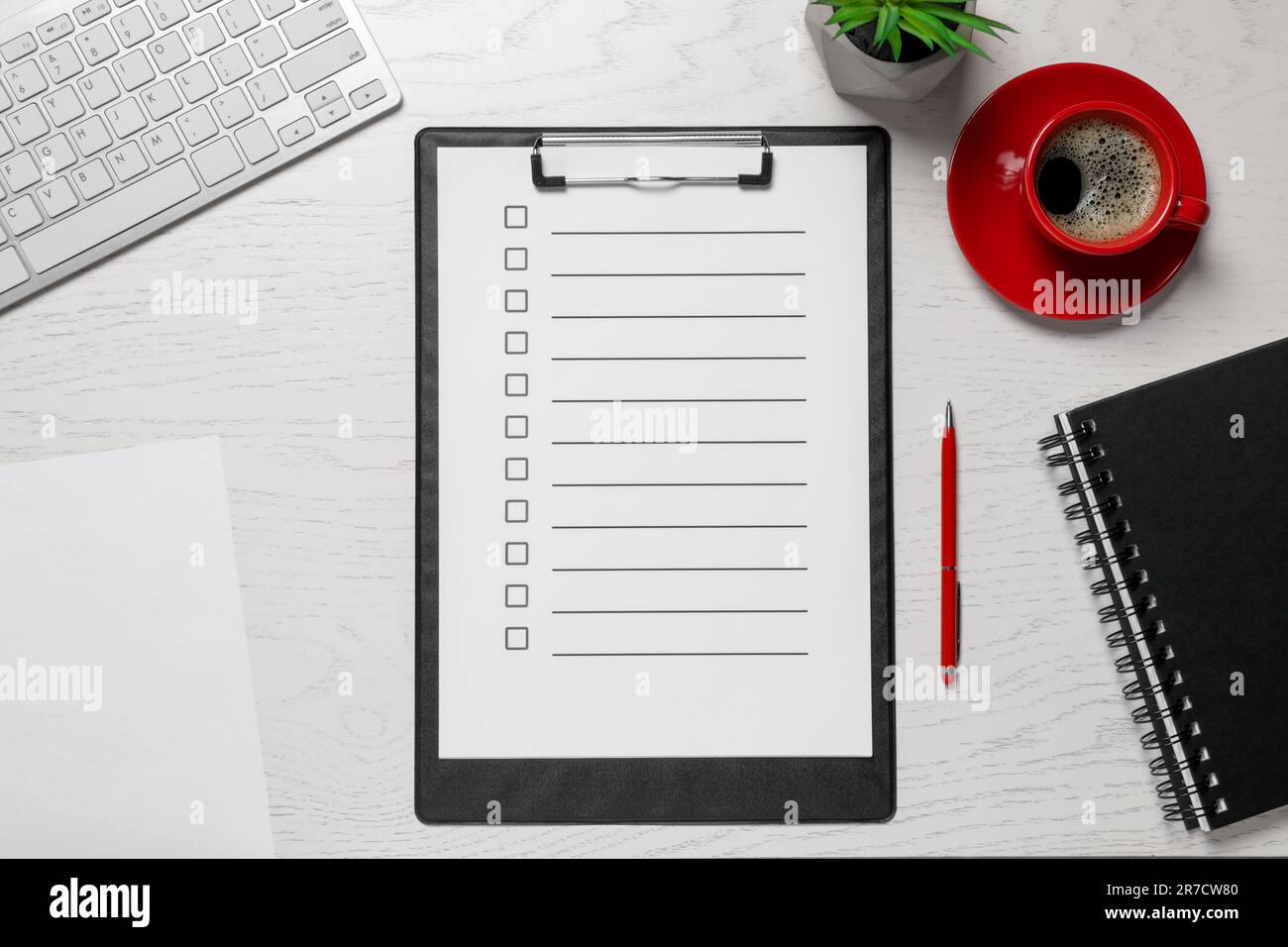 Clipboard with checkboxes, cup of coffee, plant and computer keyboard ...