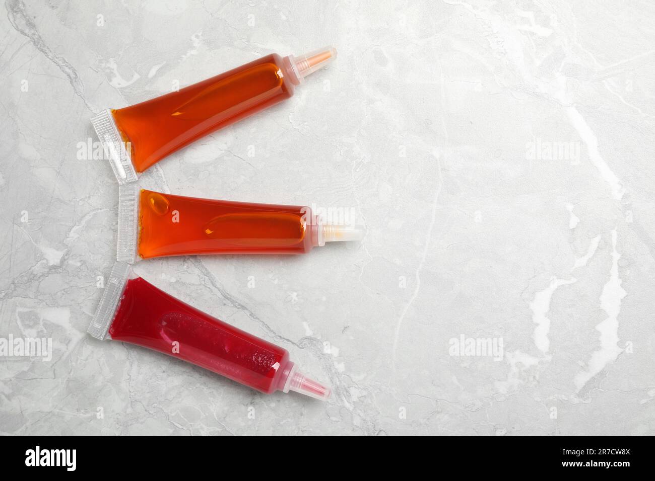 Tubes with food coloring on light grey marble table, flat lay. Space ...