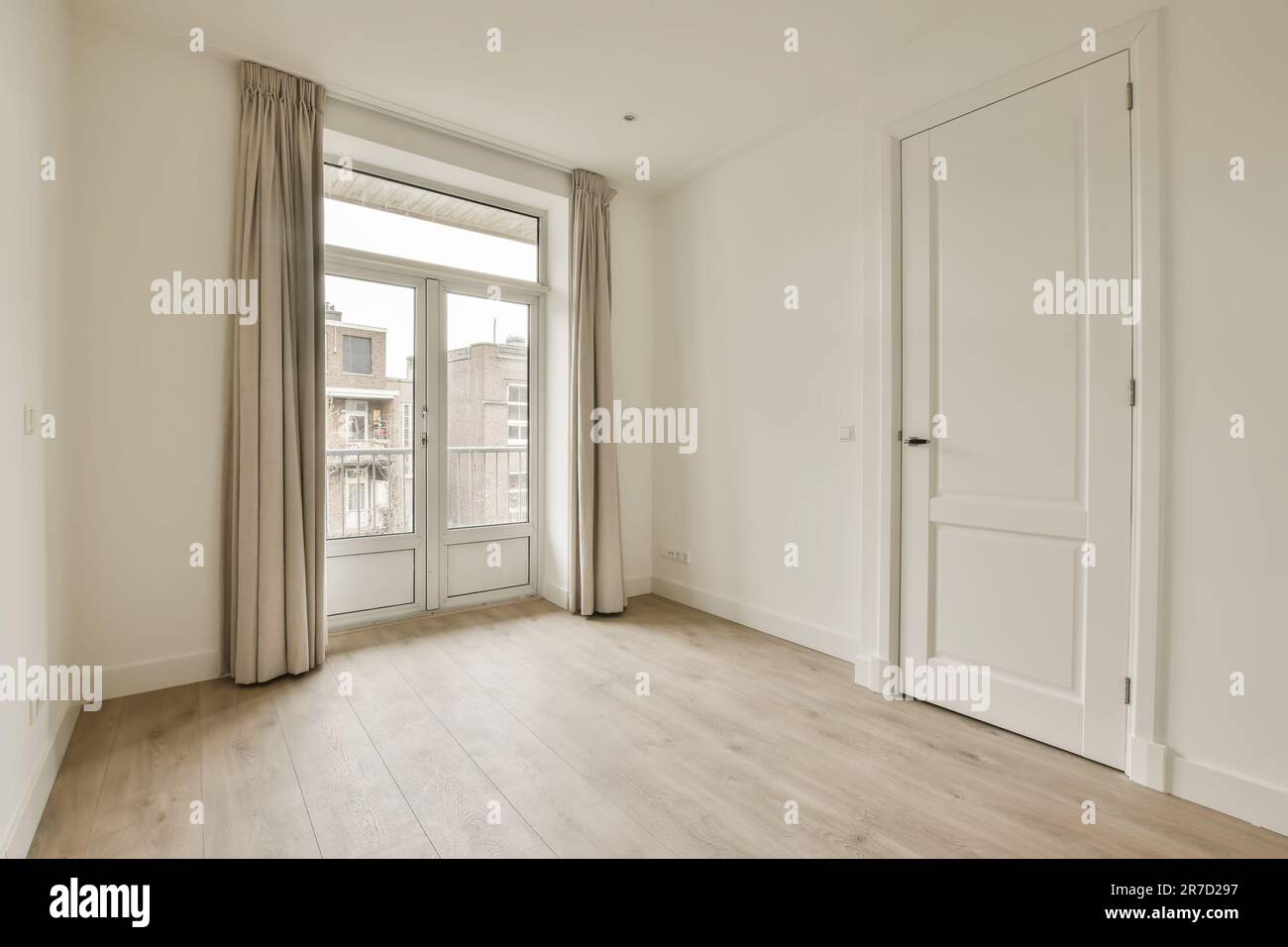 an empty room with wooden floors and white walls, there is a door ...