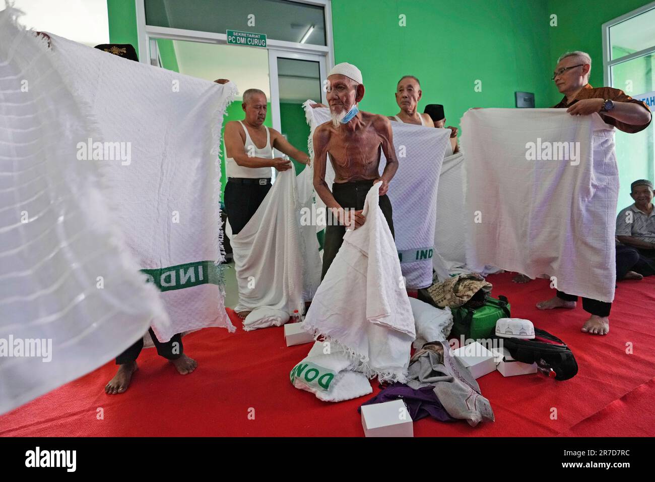 Husin bin Nisan, center, with other worshippers, prepares to wear a ...