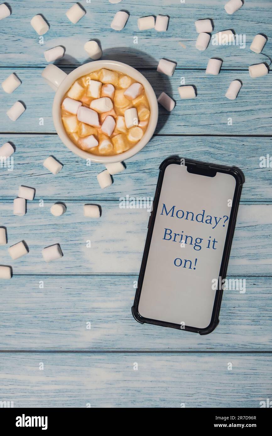 MONDAY BRING IT ON concept text on mobile phone screen with white cup ...