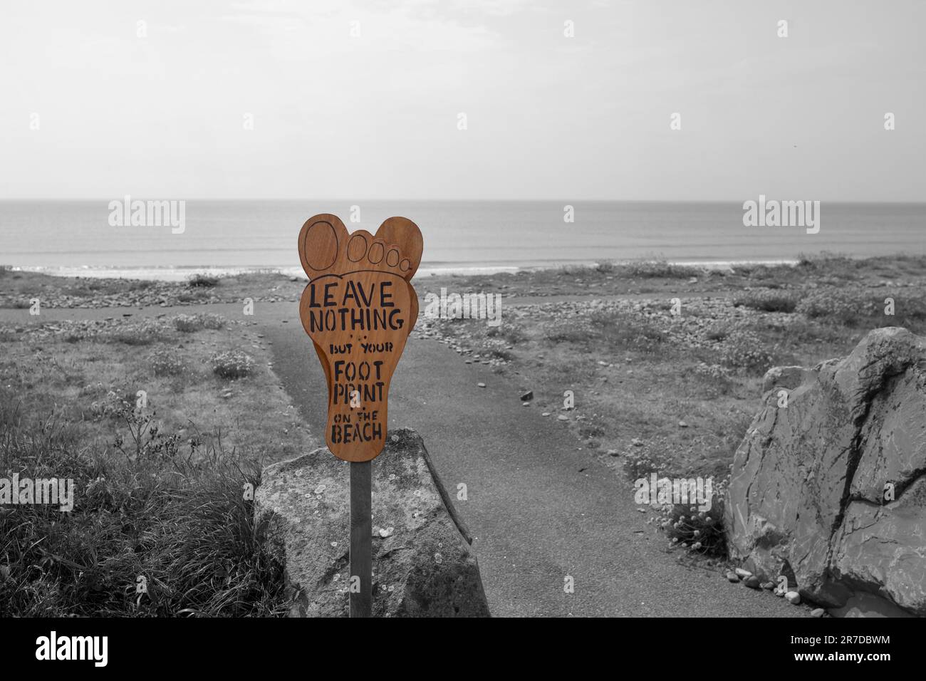 Wooden no littering sign in the shape of a foot. It reads Leave nothing ...
