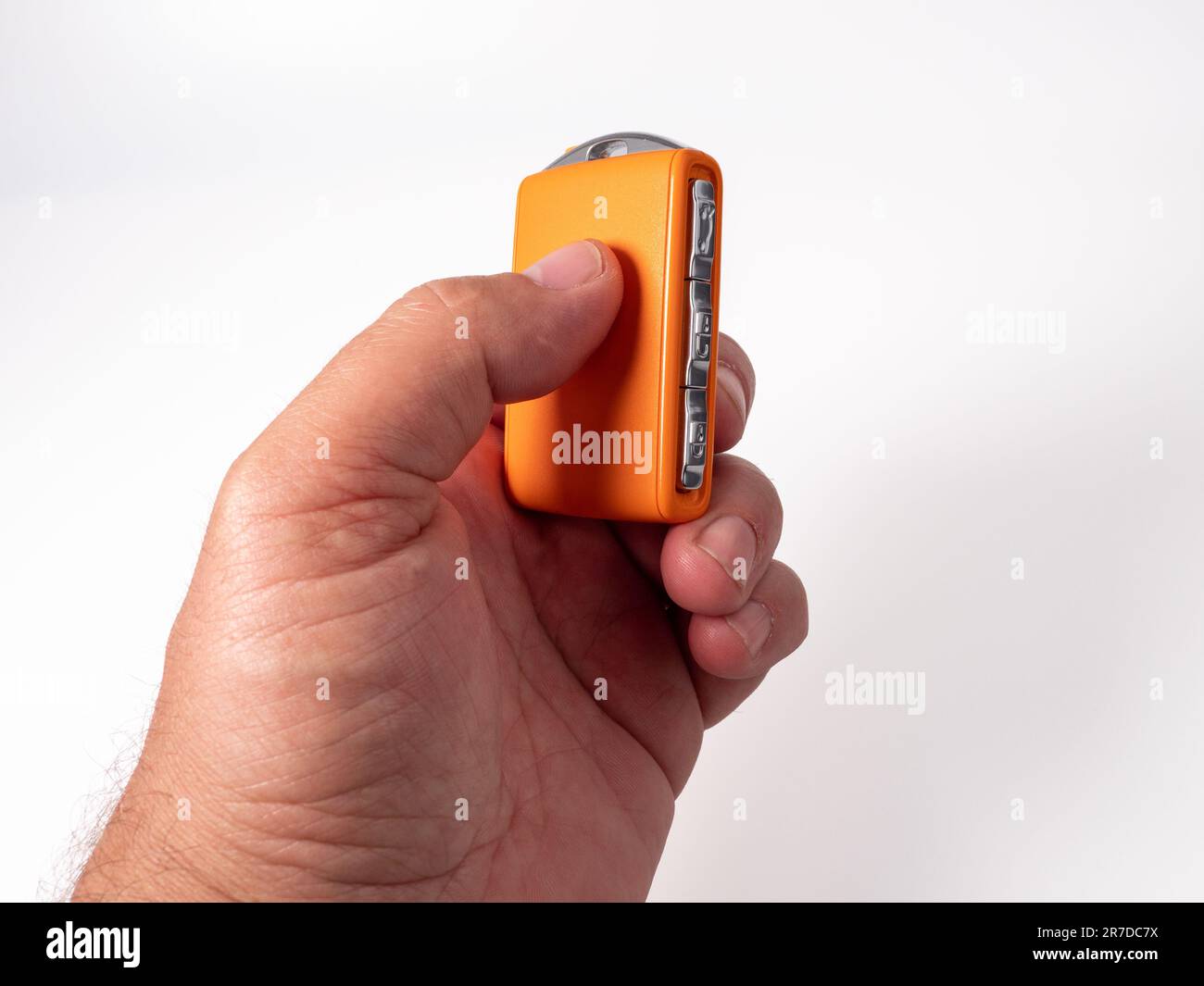 Modern wireless orange ignition key in hand on a white background ...