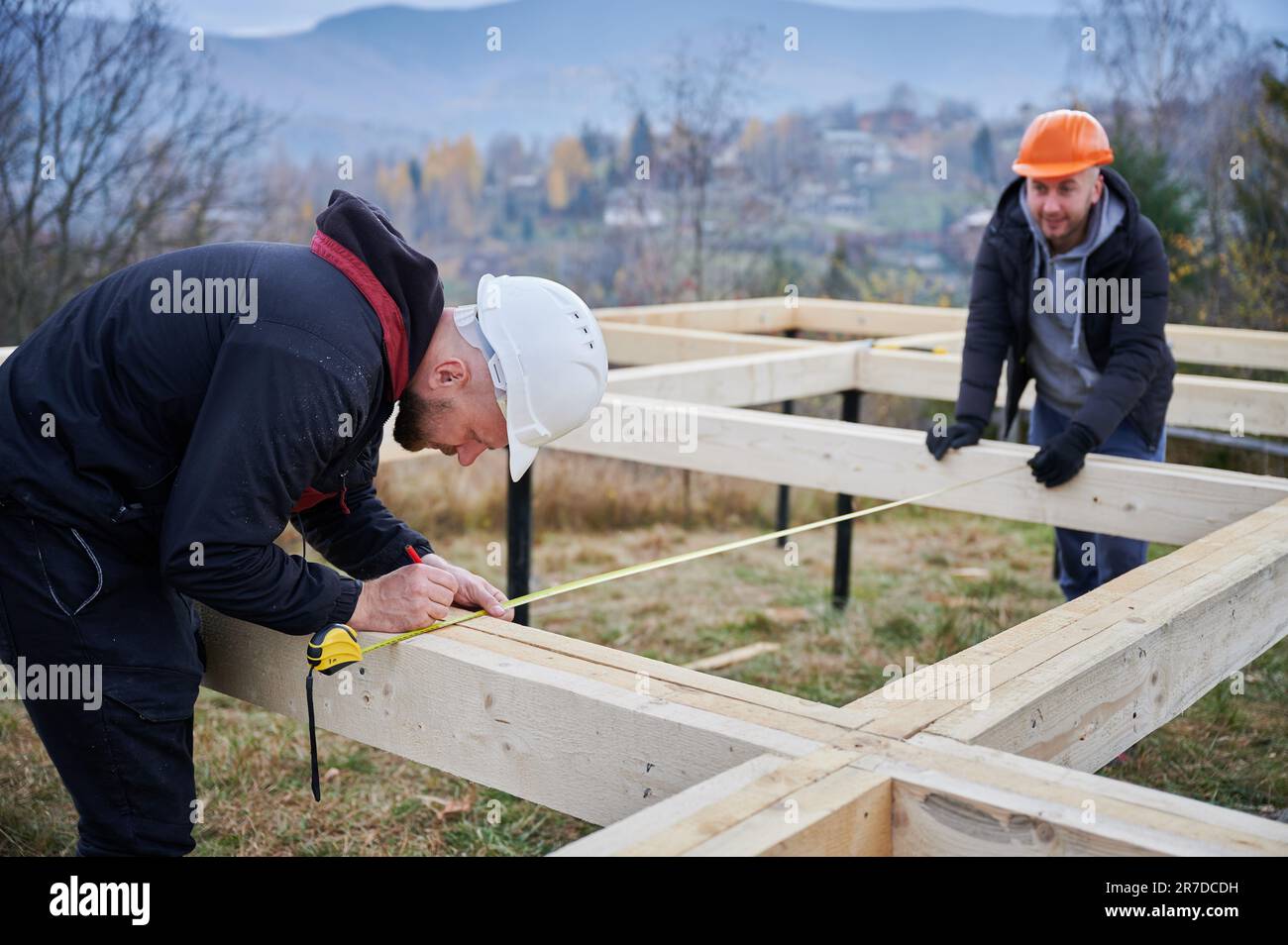Man worker building wooden frame house on pile foundation. Carpenter ...