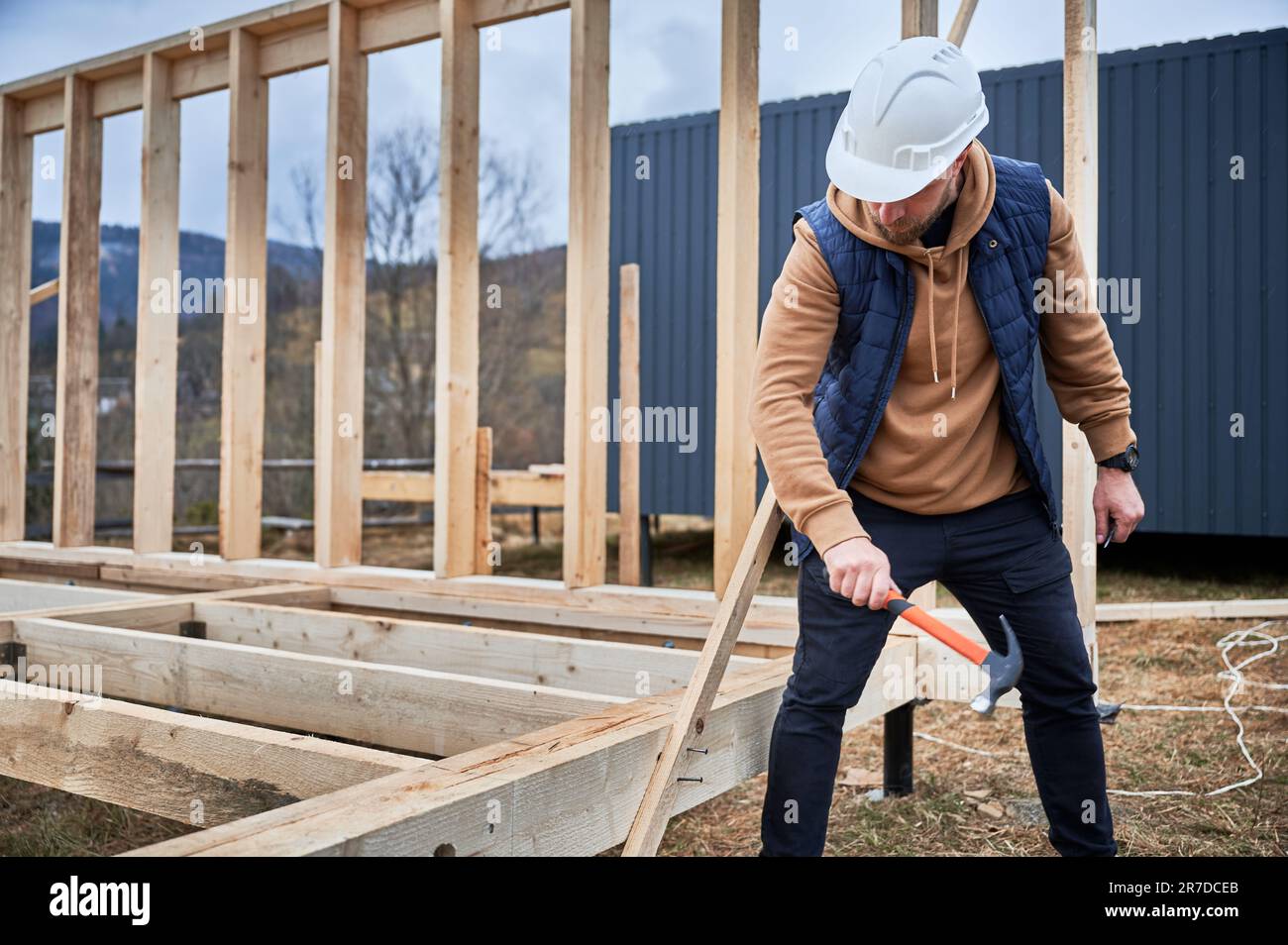 Man worker building wooden frame house on pile foundation. Carpenter ...