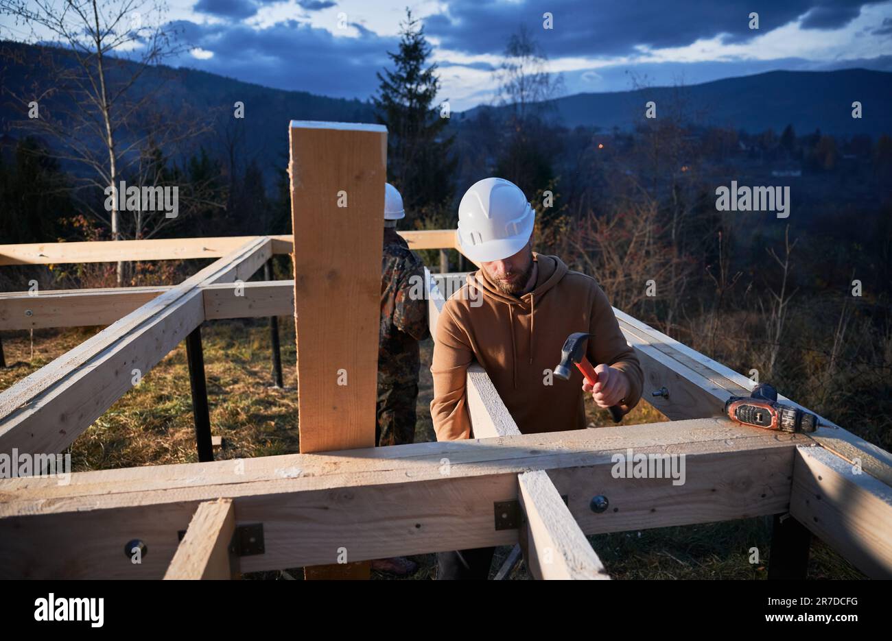Men workers building wooden frame house on pile foundation. Carpenters ...