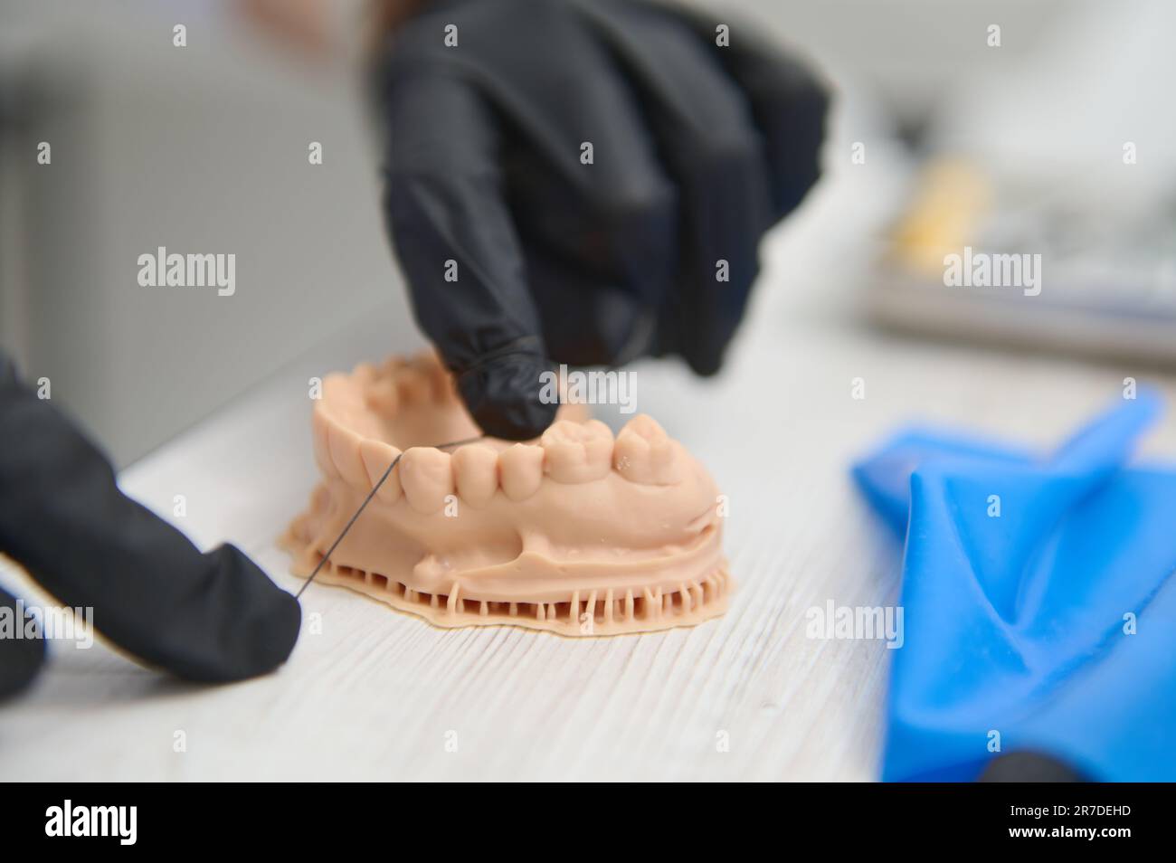 Focus on hands of dentist in black sterile gloves using dental floss ...