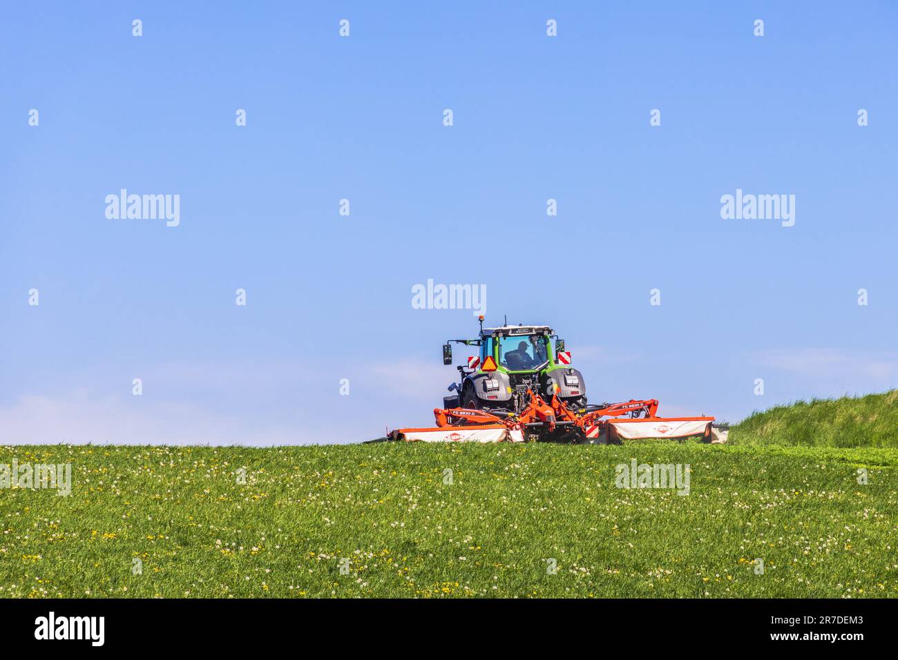 Harvesting grass on a field with a mower after a tractor Stock Photo ...
