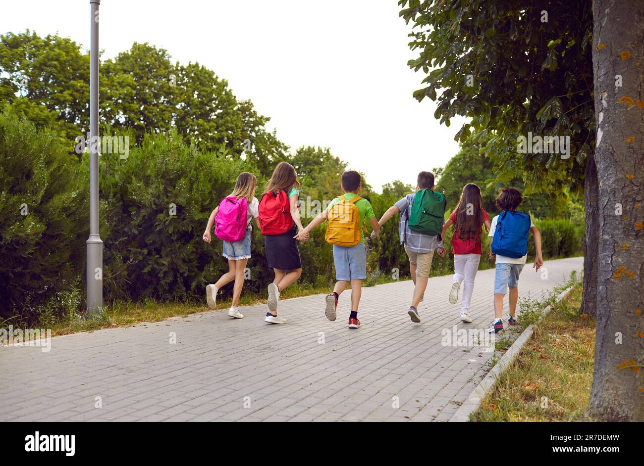Group of students with backpacks running along the park path on their ...