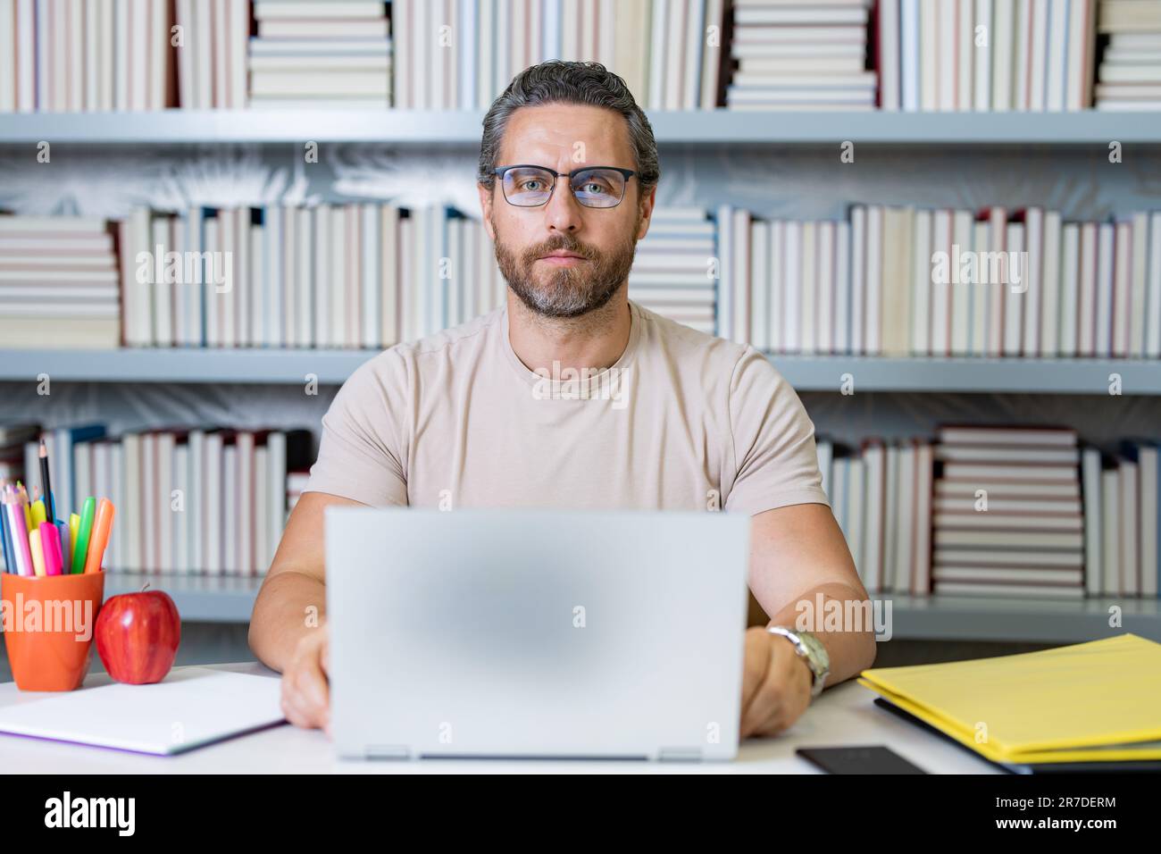 Portrait of school teacher with laptop in classroom. Handsome teacher ...