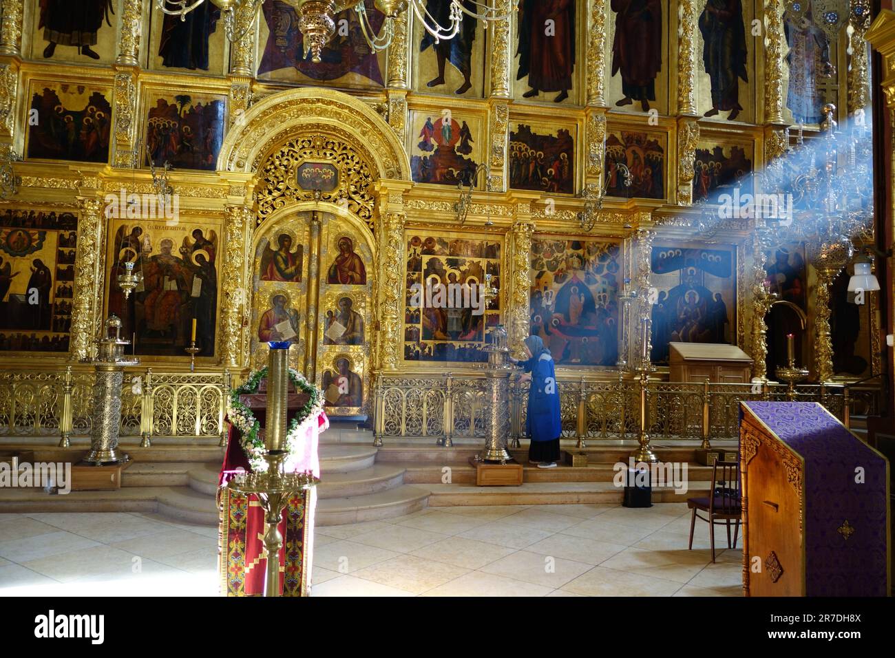 An elderly woman in a peaceful pose, in prayer as she kneels in front ...