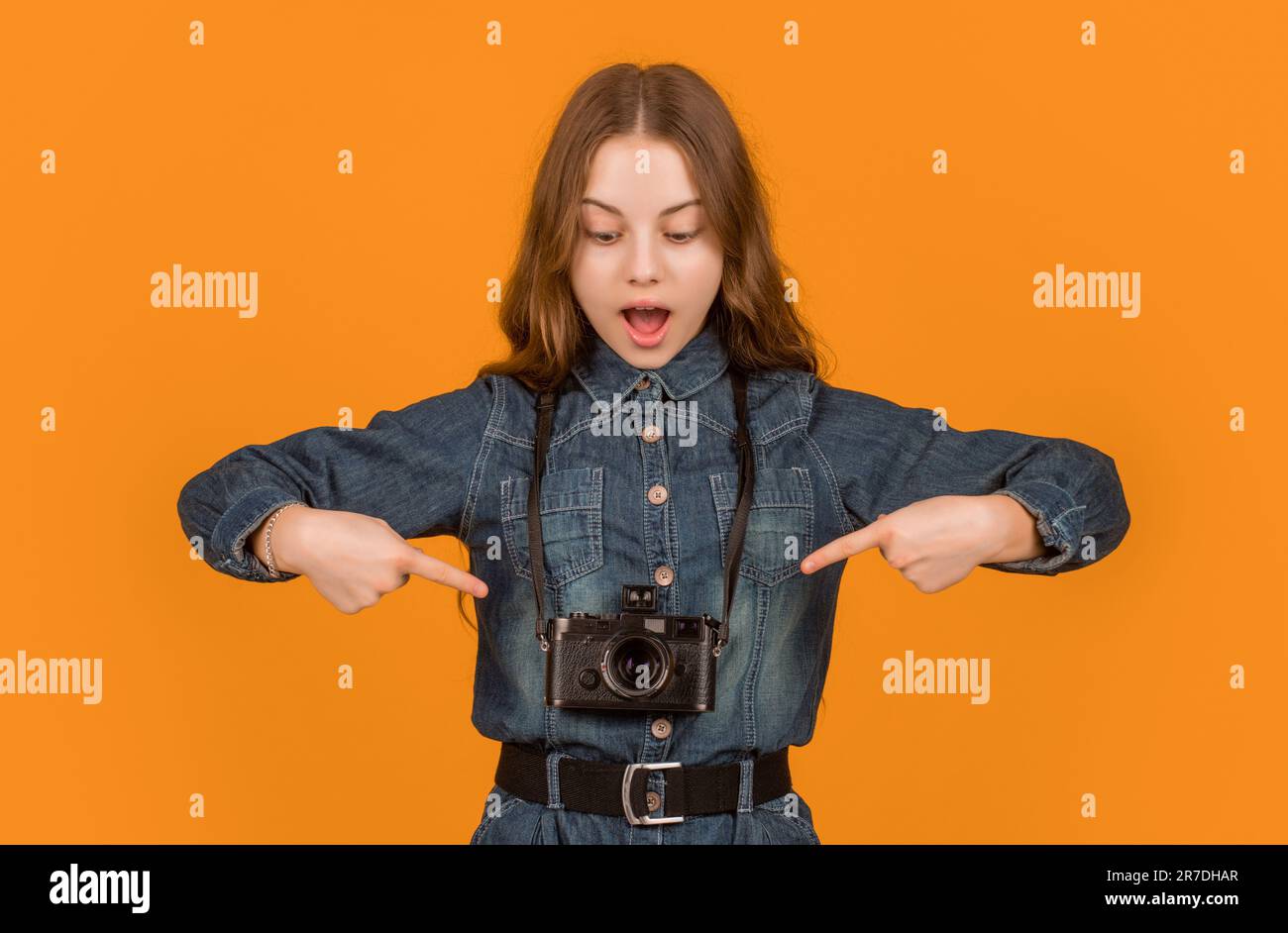 Surprised girl photographer pointing fingers at camera hanging on neck ...