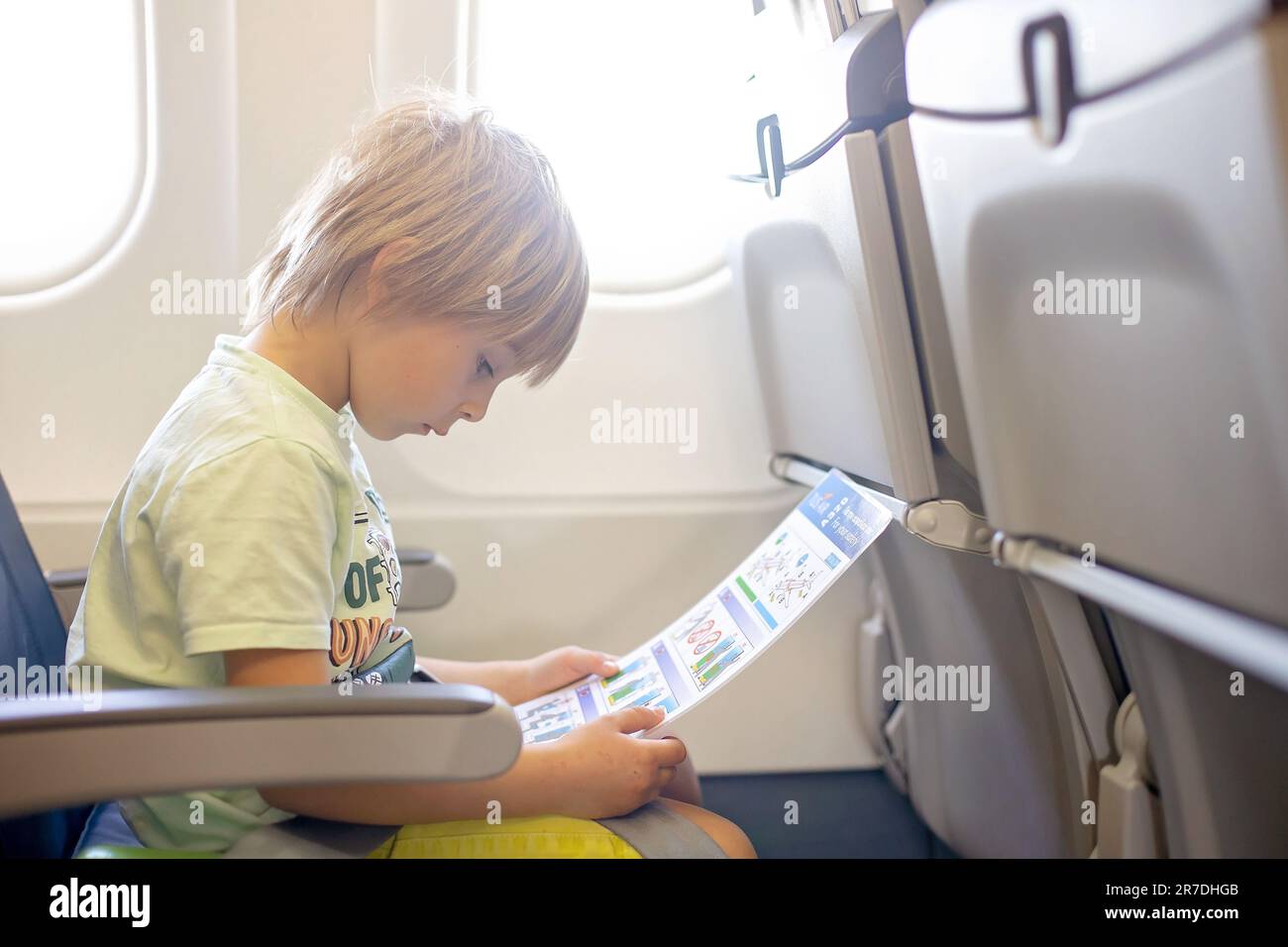 Cute preschool child, flying on a long distant flight, eating burger in ...